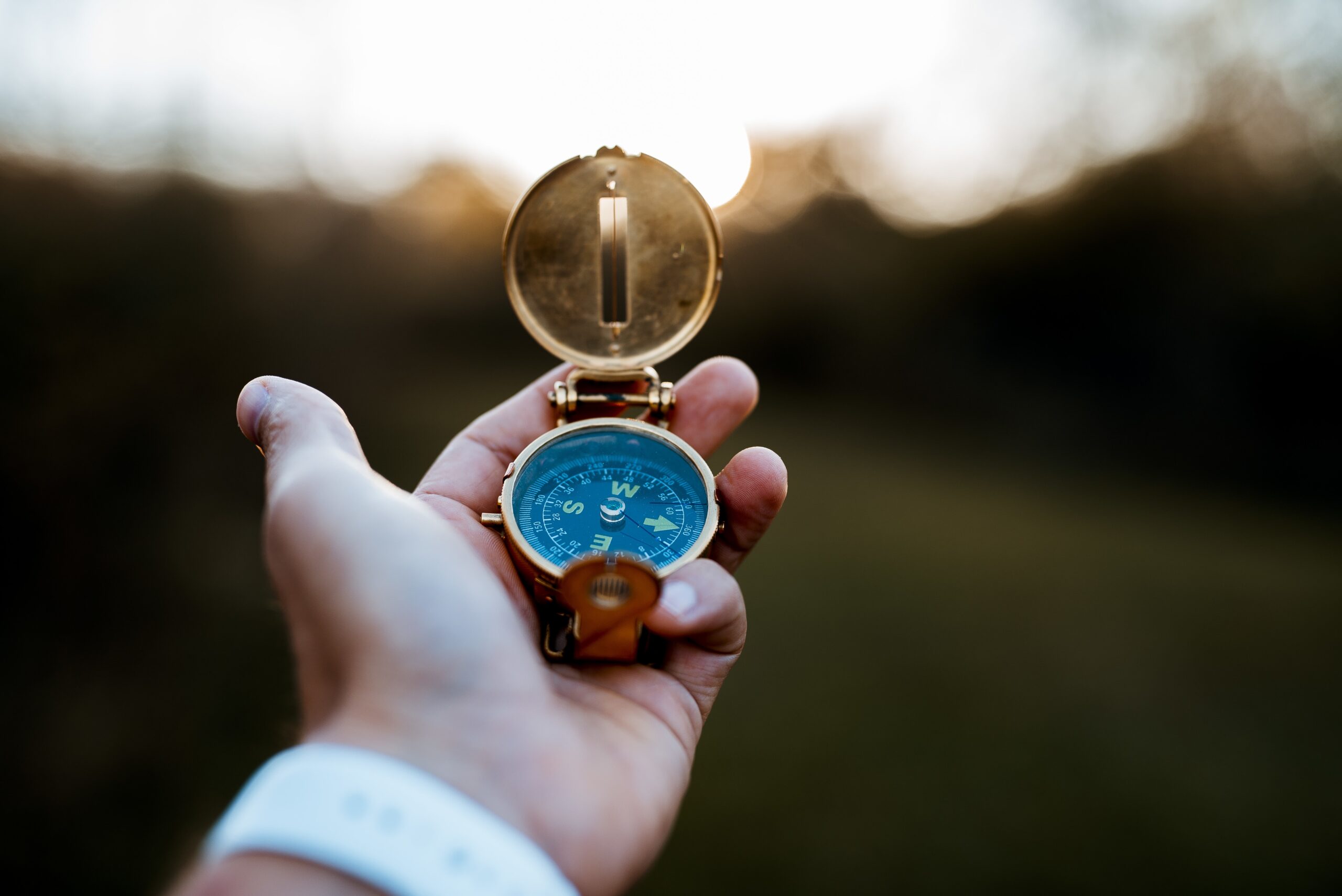 A closeup shot of a person holding a compass with a blurred background